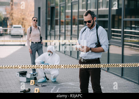 female and male detectives in sunglasses together inspect the crime ...