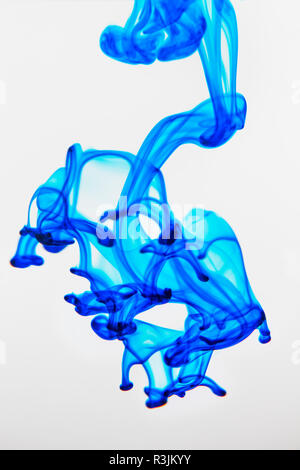 Food coloring dropped into glass of water and dispersing Stock Photo ...