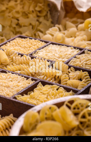 Wooden boxes with different types of uncooked pasta on color background ...