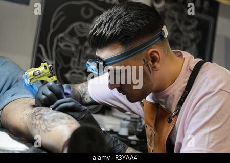 A Tattoo artist seen hitting a tattoo on a client at the tattoo parlour ...