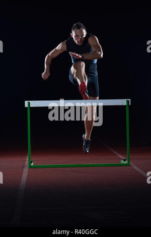 Athletics, man moving hurdles Stock Photo - Alamy