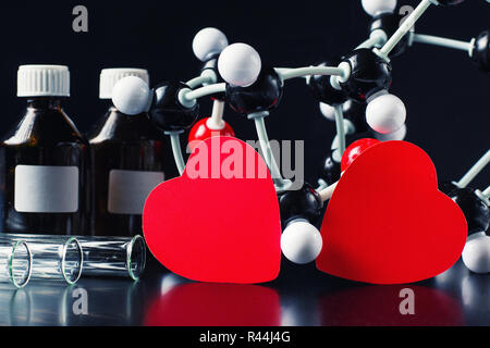 Two red paper hearts and molecular structure model on black background ...