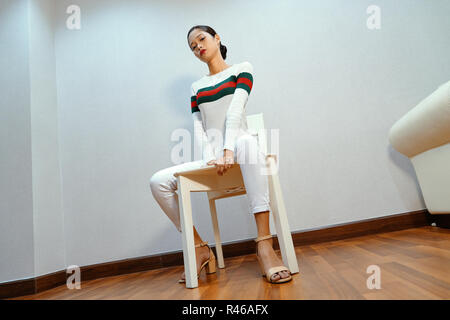 Beautiful woman posing -open legs, sitting on chair, looking at camera ...