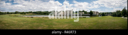 A view of Leeds Castle surrounded by a moat viewed through the trees ...