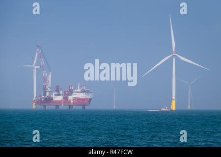 The jack-up crane vessel MPI Discovery lifts a wind turbine mast at the ...