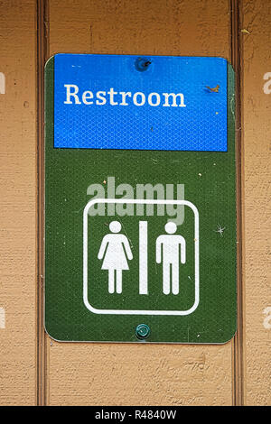 A blue restroom sign with male and female symbols is mounted on a ...