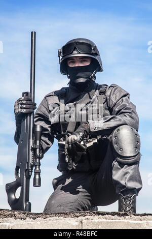 SWAT police operator with sniper rifle kneeling on top of a roof Stock ...