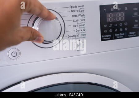 Person adjusting temperature dial of a washing machine Stock Photo - Alamy