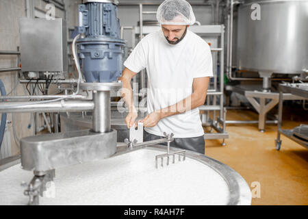 Man mixing milk in the stainless tank during the fermentation process ...