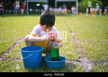 Children compete in fill-the-bottle game during their kindergarten ...