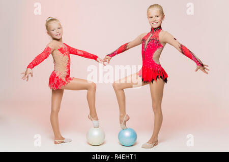 two cute gymnast child girl show athletic skills on white studio ...