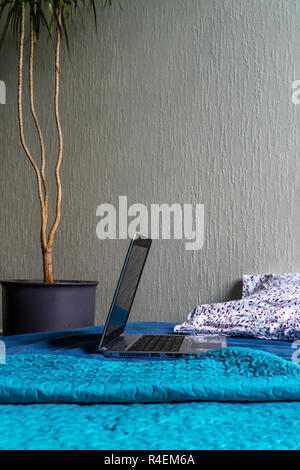 Grey Laptot Laying on Mattress with Turquoise Cover, Few Pillows and a ...