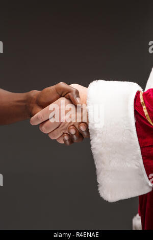 The handshake of Santa Claus hand and hand of african man. Merry ...