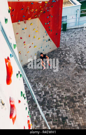 Alpinist practicing indoor rock-climbing on artificial boulder without ...