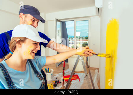 Beautiful couple painting room yellow with paintbrush in theri new ...