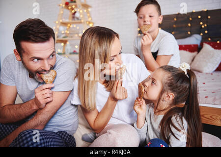Playful family eating gingerbread cookies at home. Mom, father and ...