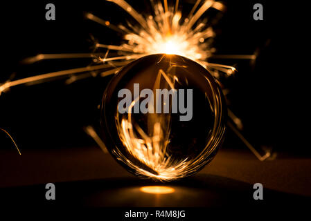 Burning sparkler behind a glass ball on a black background Stock Photo ...
