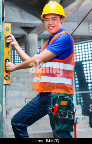 Builder or worker controlling wall on construction site Stock Photo - Alamy