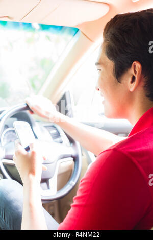 Asian man texting while driving Stock Photo - Alamy