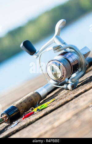 fishing rod on jetty close to lake Stock Photo - Alamy