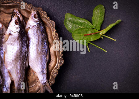 dried tar ram in a copper plate on a black surface, near a pile of ...