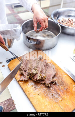 The cook cuts boiled beef meat on wooden cutting board Stock Photo - Alamy