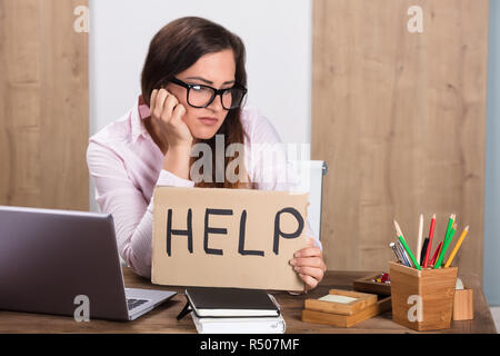 Sad businesswoman holding a help sign Stock Photo - Alamy