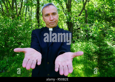 A good looking serious catholic priest is studying, reading the Bible ...