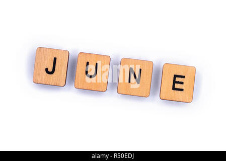 JUNE, spelt with wooden letter tiles over a plain white background ...