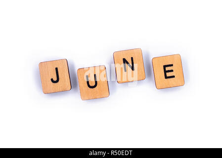 JUNE, spelt with wooden letter tiles over a plain white background ...