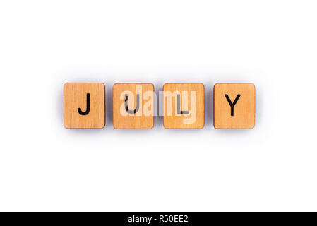 JULY, spelt with wooden letter tiles over a plain white background ...