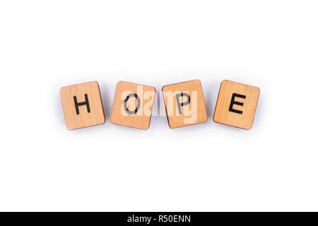 The word HOPE, spelt with wooden letter tiles over a plain white ...