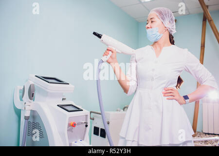 specialist keeps hand piece for hair removal in the hands for cosmetic ...