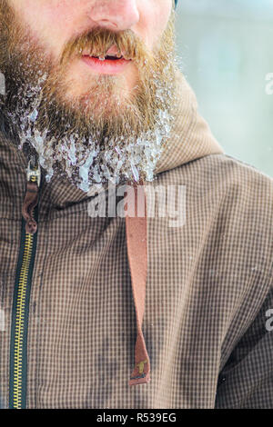 Part of the face of a serious and worried man is an icy beard with ...