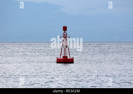 Small red navigational buoy with light on top and solar panels for ...