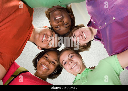 Portrait of four college students talking while studying at classroom ...