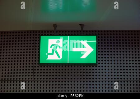 Big Emergency fire exit sign is placed on the black wall over the door ...