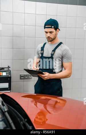 auto mechanic with notepad examining car at auto repair shop Stock ...