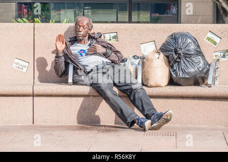 Homeless African American elderly man reclining under a bridge in ...
