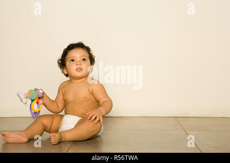 Cute Black Baby Playing With Rattle Toy While Lying On Bed Stock Photo ...