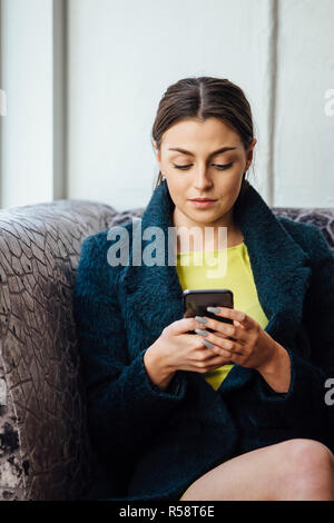 Woman concentrating on her phone while telecommuting from a local ...