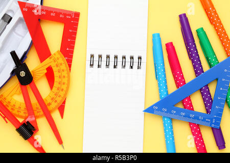 Multicolored pen, rulers and notebook on yellow background Stock Photo ...