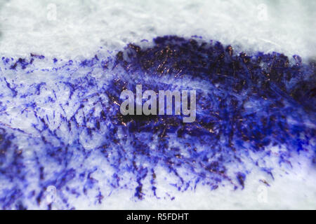 Dripping blue Ink on Paper under the microscope. The paper absorbs blue ...