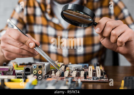 cropped shot of computer engineer repairing motherboard with ...