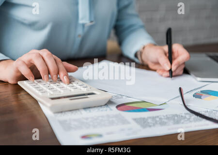 Cropped hands using calculator and writing in notebook for tax ...