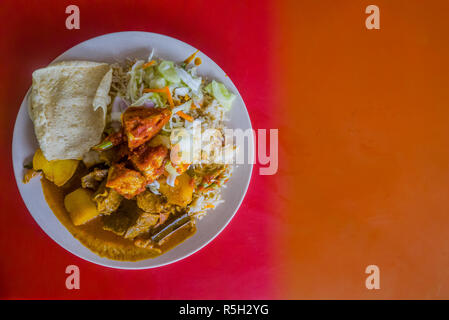 Vibrant red spicy chicken curry with green peppers onions served on ...