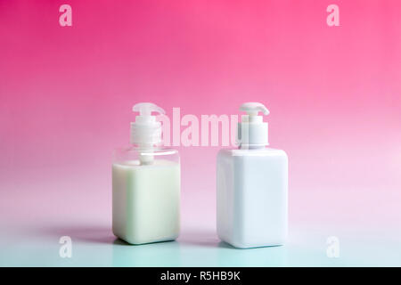 two rectangular pump bottles : white and transparent, on a gradient ...