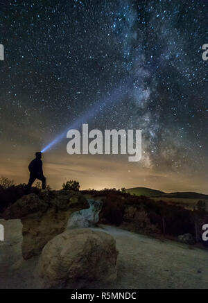 Man with a flashlight trying to light up the night sky and the milky ...