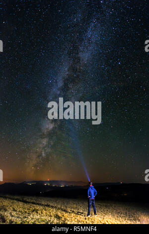 Man with a flashlight trying to light up the night sky and the milky ...