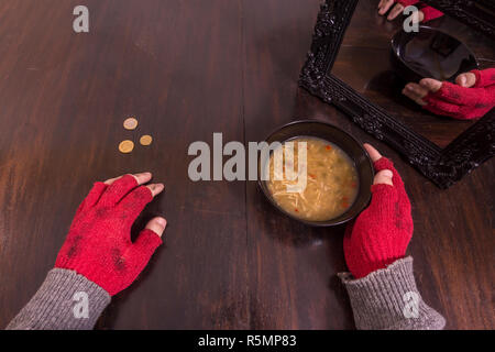 Poverty concept. Man with red gloves holding a metal bowl of soup ...